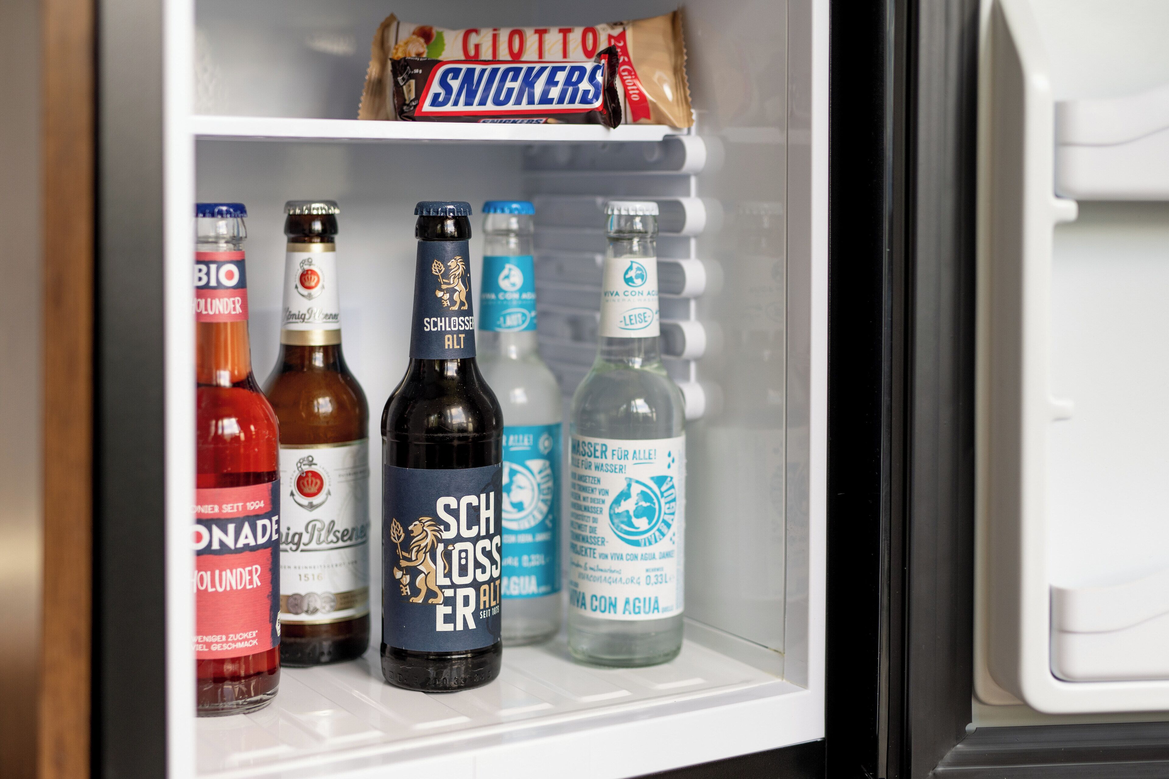 Geladeira com diversas bebidas, incluindo uma garrafa de vinho tinto, uma garrafa de cerveja e várias garrafas de água.