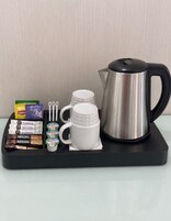 Uma bandeja com uma cafeteira, duas xícaras brancas, talheres e alguns alimentos, incluindo chá Lipton e café Nescafé.
