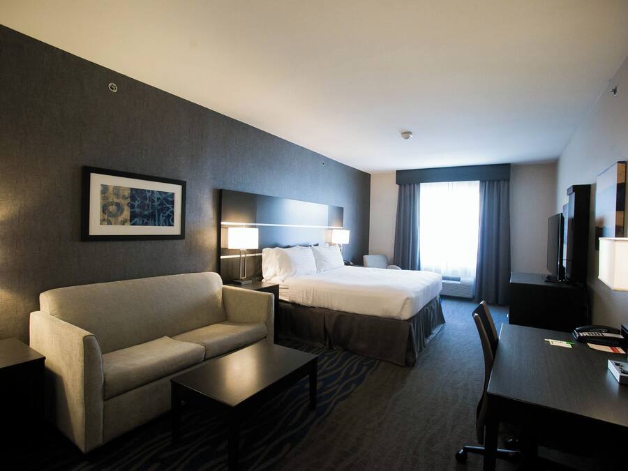 Quarto de hotel com cama, sofá, escrivaninha e televisão.