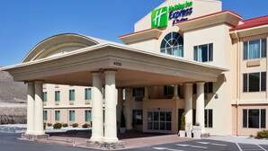 Um hotel Holiday Inn Express com entrada coberta, colunas e céu claro.