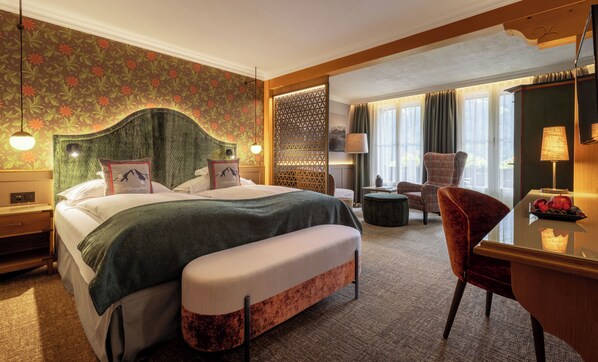 Quarto de hotel com uma cama grande, uma escrivaninha, uma cadeira e um painel de cabeceira decorativo.