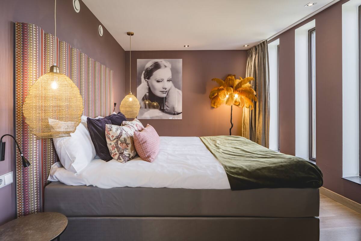 Quarto moderno com cama grande, decoração de parede estampada e uma janela ampla.