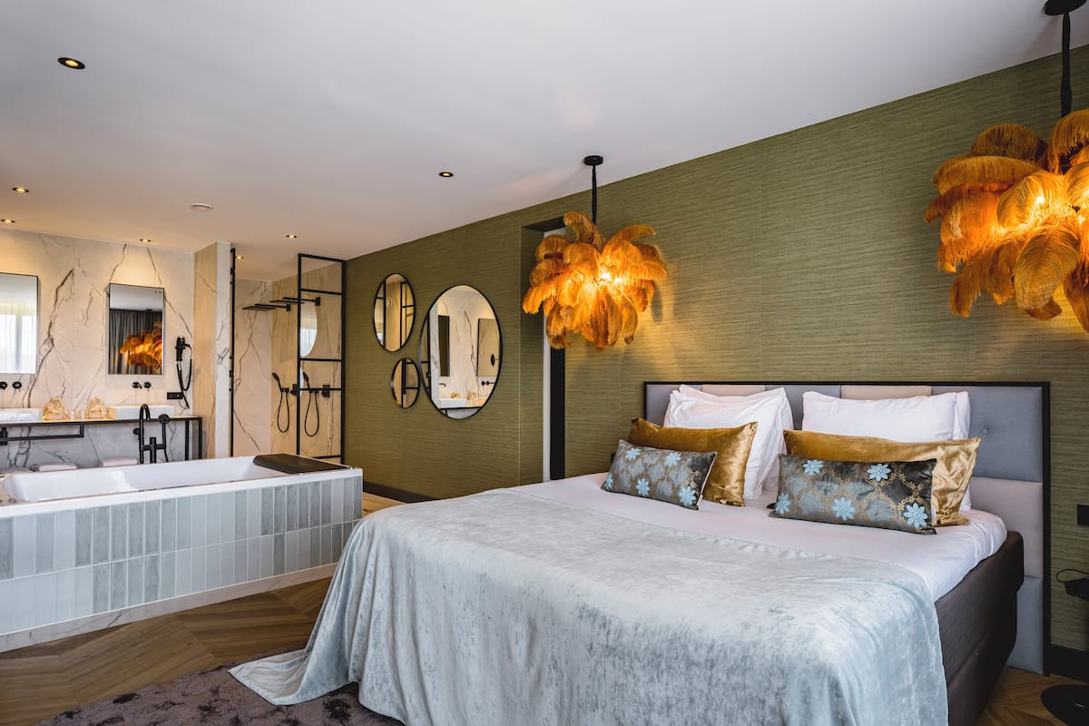 Um quarto moderno com uma cama grande, uma banheira embutida e uma toucador com espelho.