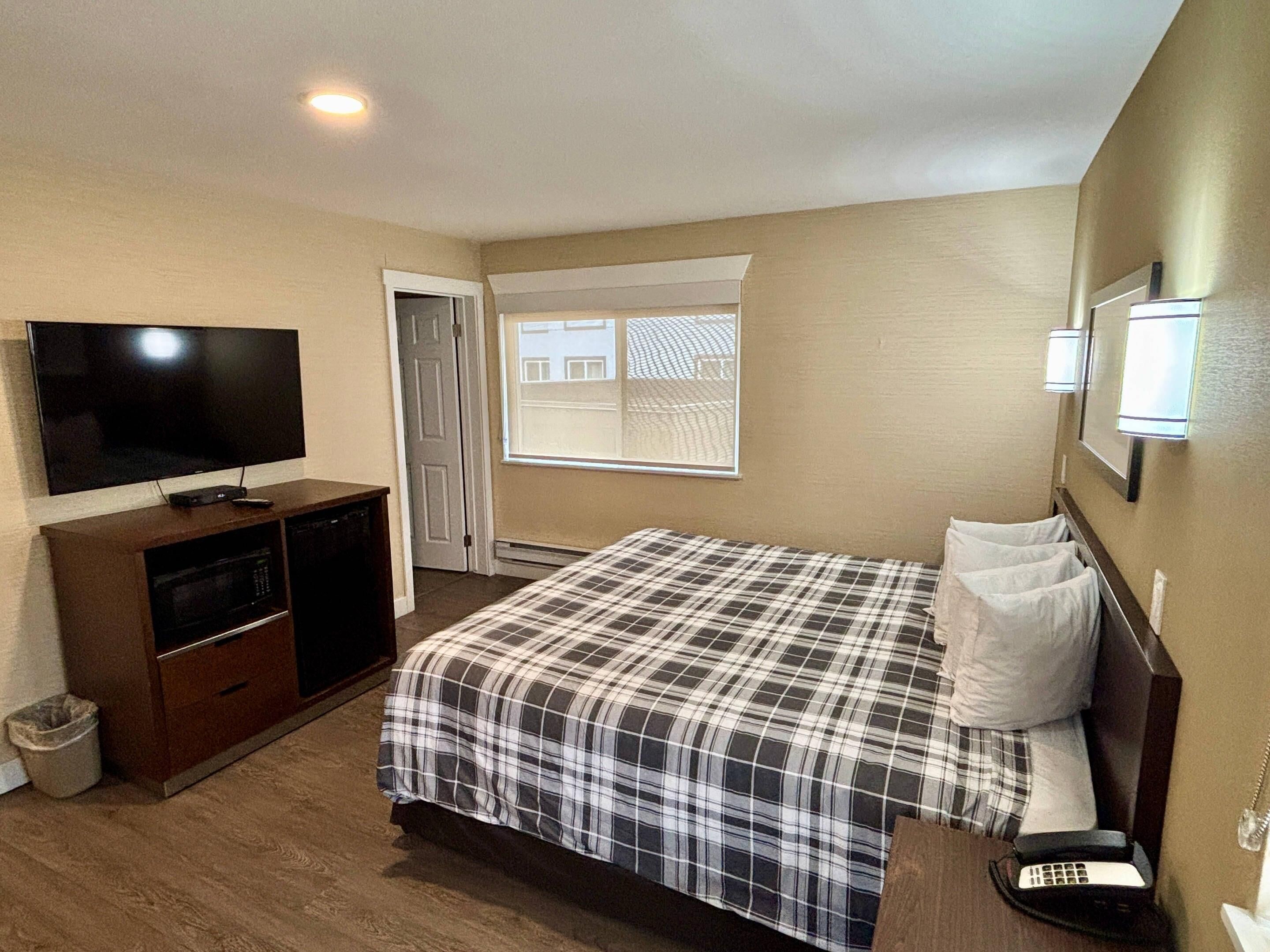 Quarto com uma cama, televisão, escrivaninha e janela.