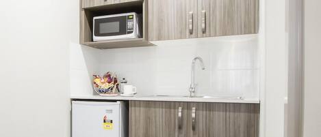 Uma cozinha compacta equipada com micro-ondas, pia e frigorífico.