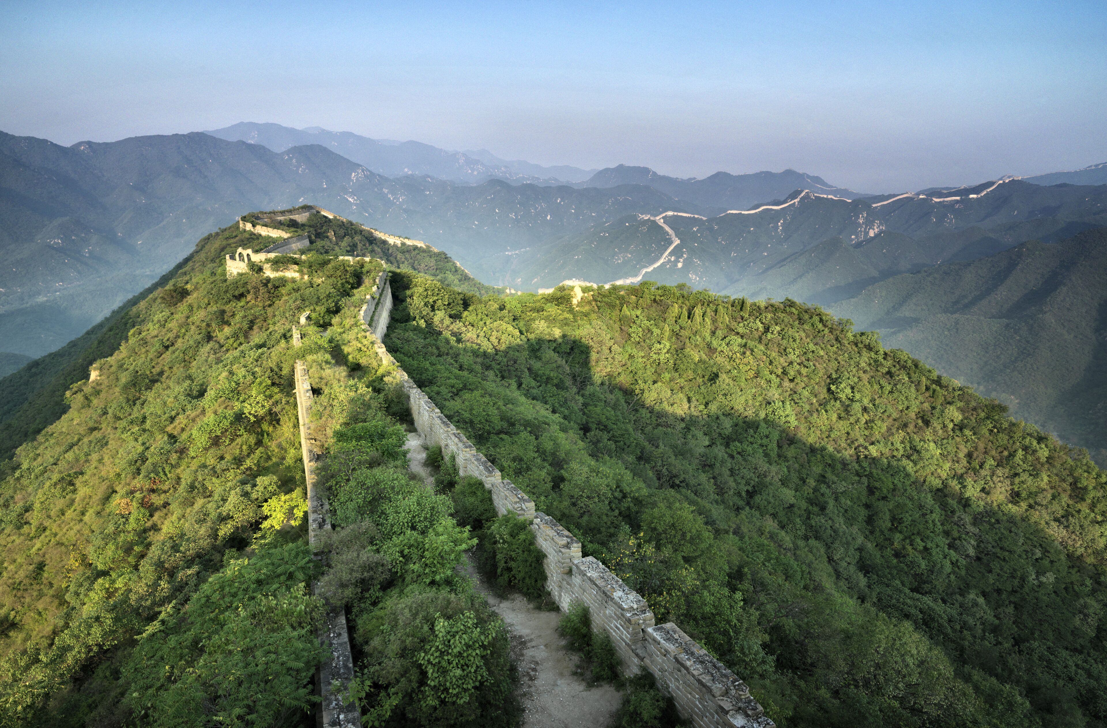 Uma vista panorâmica da Grande Muralha da China, serpenteando por montanhas verdejantes.