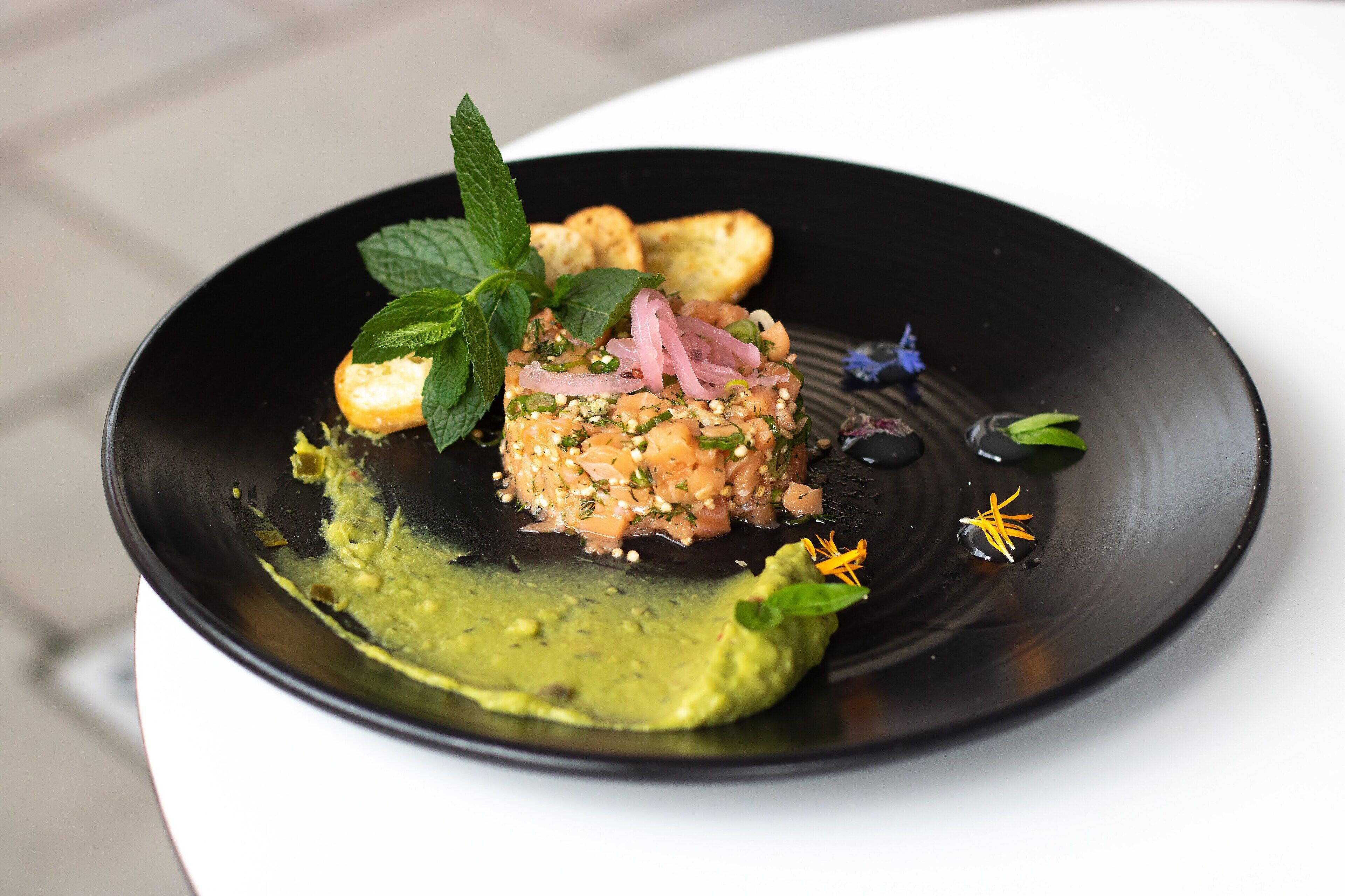 Prato com molho verde, uma fatia de pão e um enfeite de hortelã.