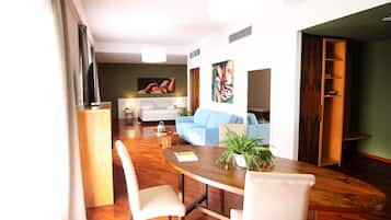 Uma sala de estar moderna com área de jantar, sofá, mesa de centro e televisão.