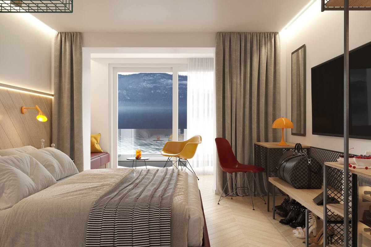 Quarto de hotel com uma cama, uma escrivaninha, uma cadeira, uma televisão e vista para a água.