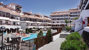 Um hotel com piscina, várias varandas e um céu limpo.