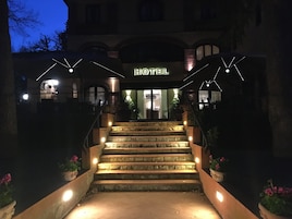 Entrada de hotel com placa, degraus de pedra e vasos de plantas.