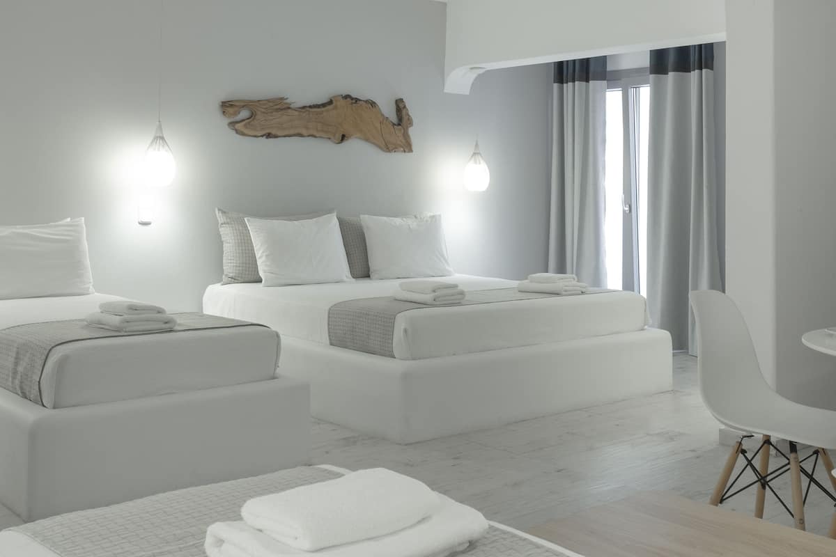 Quarto de hotel moderno com duas camas, decoração de parede em madeira e vista para a cidade.