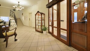 Um saguão de hotel com escada, balcão de recepção, um armário de madeira grande e uma planta em vaso.