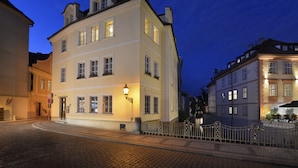 Um edifício histórico com fachada clássica, várias janelas e entrada bem iluminada.