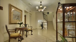 Uma sala de jantar com um candelabro, um quadro emoldurado e um aparador de vidro com copos.