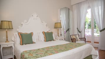 Quarto bem arrumado com uma cama grande, duas mesas de cabeceira com luminárias, uma cadeira e vista para o exterior através de uma janela com cortinas.