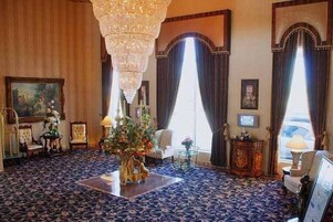 Quarto de hotel com um lustre grande, um arranjo floral e um tapete estampado.