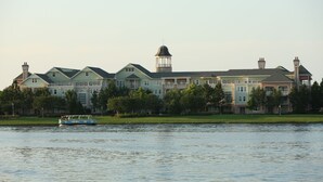 Um hotel grande com vários edifícios, um corpo de água em primeiro plano e um barco.