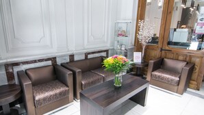 Uma área de estar com dois sofás e uma mesa de centro, um vaso com flores e um expositor de vidro.