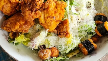 Prato de comida com frango frito, alface desfiada e outros vegetais.
