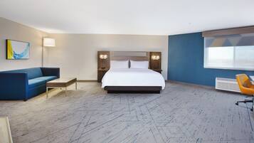 Quarto de hotel com uma cama, um sofá, uma escrivaninha e uma cadeira.