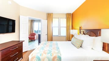 Quarto de hotel com cama, televisão, secretária e cadeira.