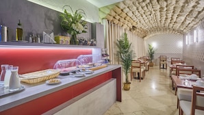 Um restaurante com balcão de buffet, mesas e cadeiras.