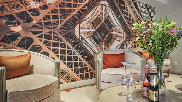 Uma sala de estar moderna com uma grande parede decorativa, dois sofás, uma mesa de centro de vidro e um vaso com flores.