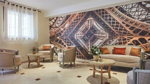 Quarto com um grande mural da Torre Eiffel, um sofá, poltronas e uma mesa de centro.