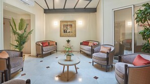 Uma sala de estar ampla, com teto alto, claraboia e uma mesa de centro rodeada por sofás e cadeiras.
