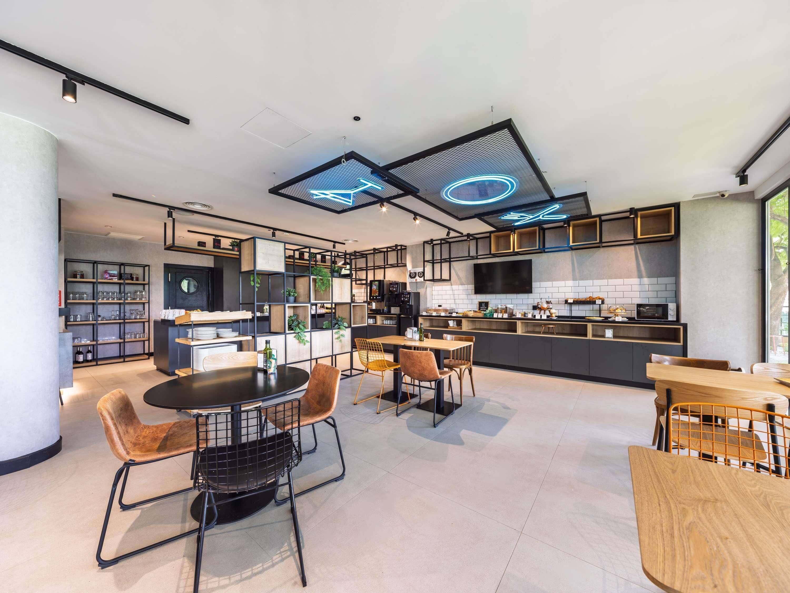 Cozinha moderna com ilha central, eletrodomésticos embutidos e área de jantar com cadeiras contemporâneas.