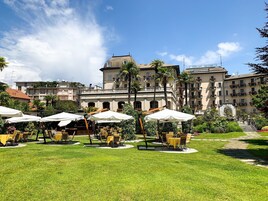 Pátio de hotel com área de estar ao ar livre e um edifício grande ao fundo.