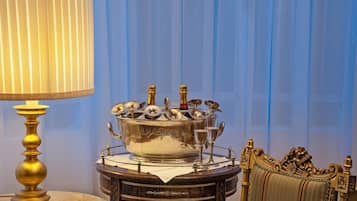 Quarto com uma mesa posta para refeição, uma luminária decorativa e uma cadeira com detalhes ornamentados.