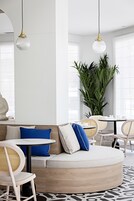 Um interior moderno com área de estar circular, cadeiras de vime e uma grande planta em vaso.