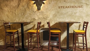 Interior de restaurante com parede de pedra, luminária em formato de cabeça de touro e a frase 'signature steakhouse' na parede.