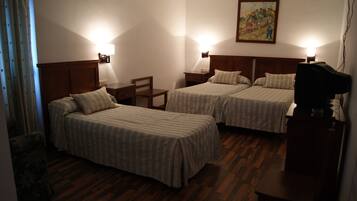 Quarto de hotel com duas camas, uma escrivaninha, uma cadeira e uma televisão.