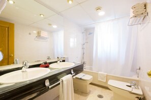 Uma casa de banho moderna com duas pias, chuveiro e banheira.