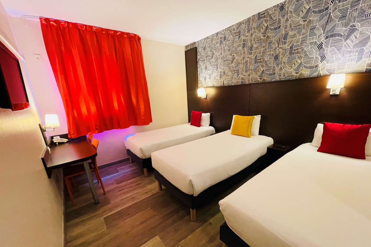 Quarto de hotel com duas camas de solteiro, uma escrivaninha e uma cadeira.