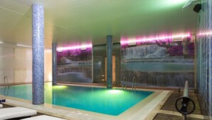 Piscina com painel de cascata, um pilar grande e área de sauna.