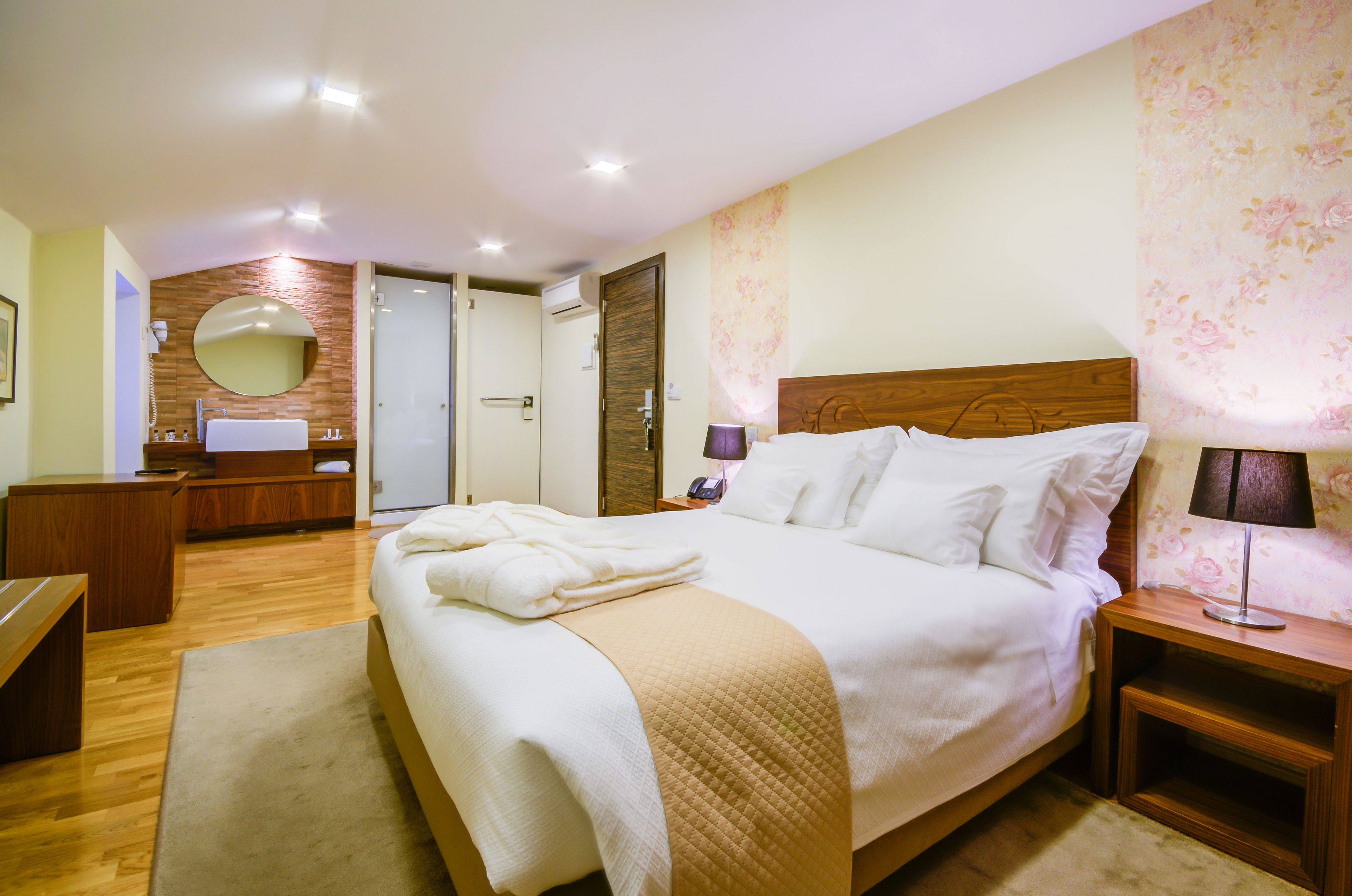 Quarto bem arrumado com uma cama grande, mesas de cabeceira, um espelho e uma cômoda de madeira.