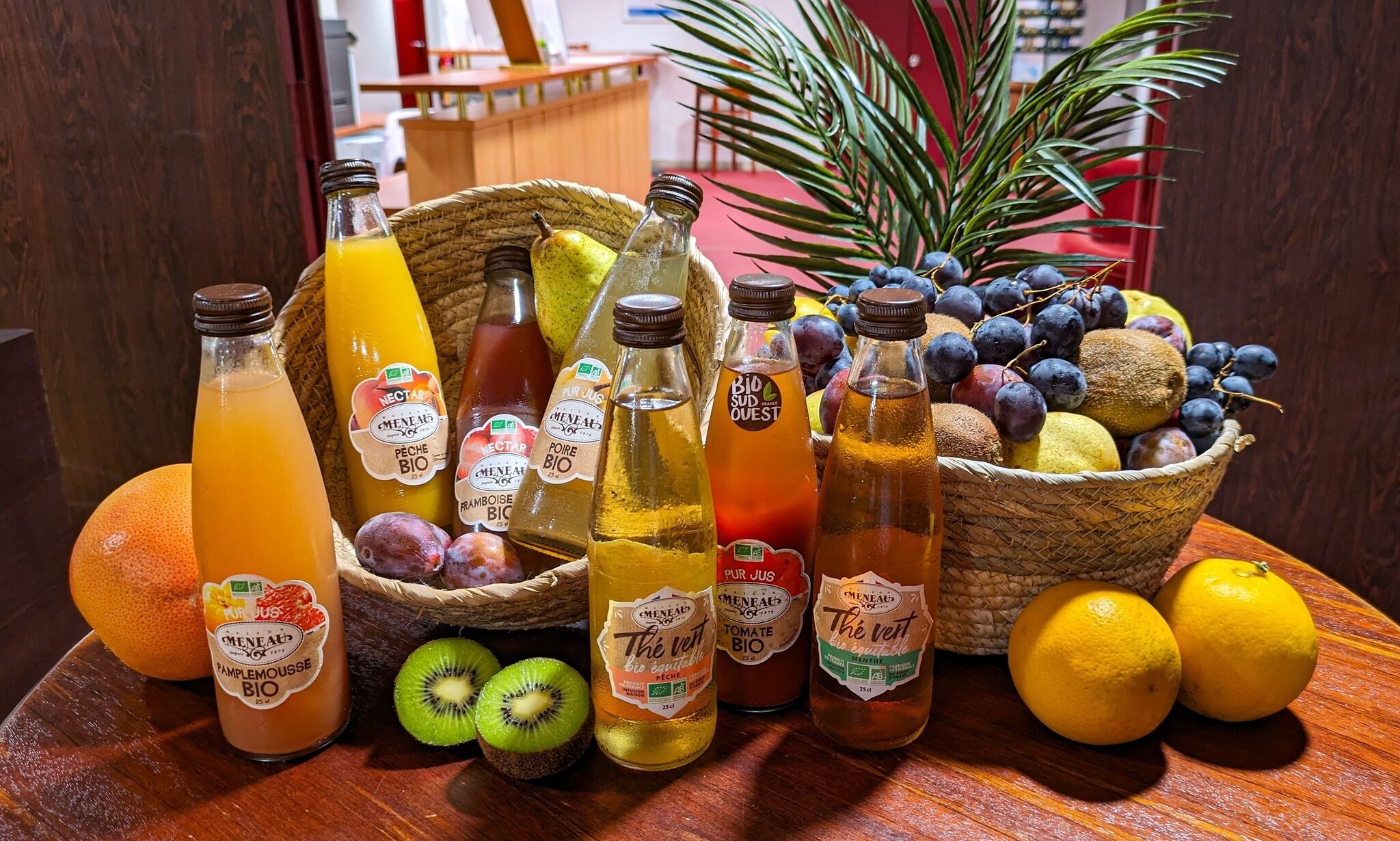 Uma mesa com diversas garrafas de bebidas e uma cesta de frutas.