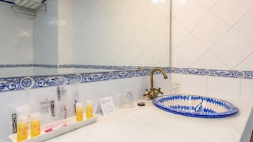 Um banheiro com pia branca, azulejos decorativos azuis e um espelho.