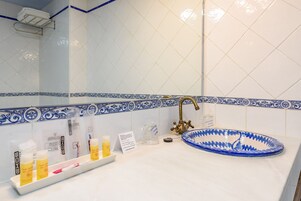 Um banheiro com pia branca, azulejos decorativos azuis e um espelho.
