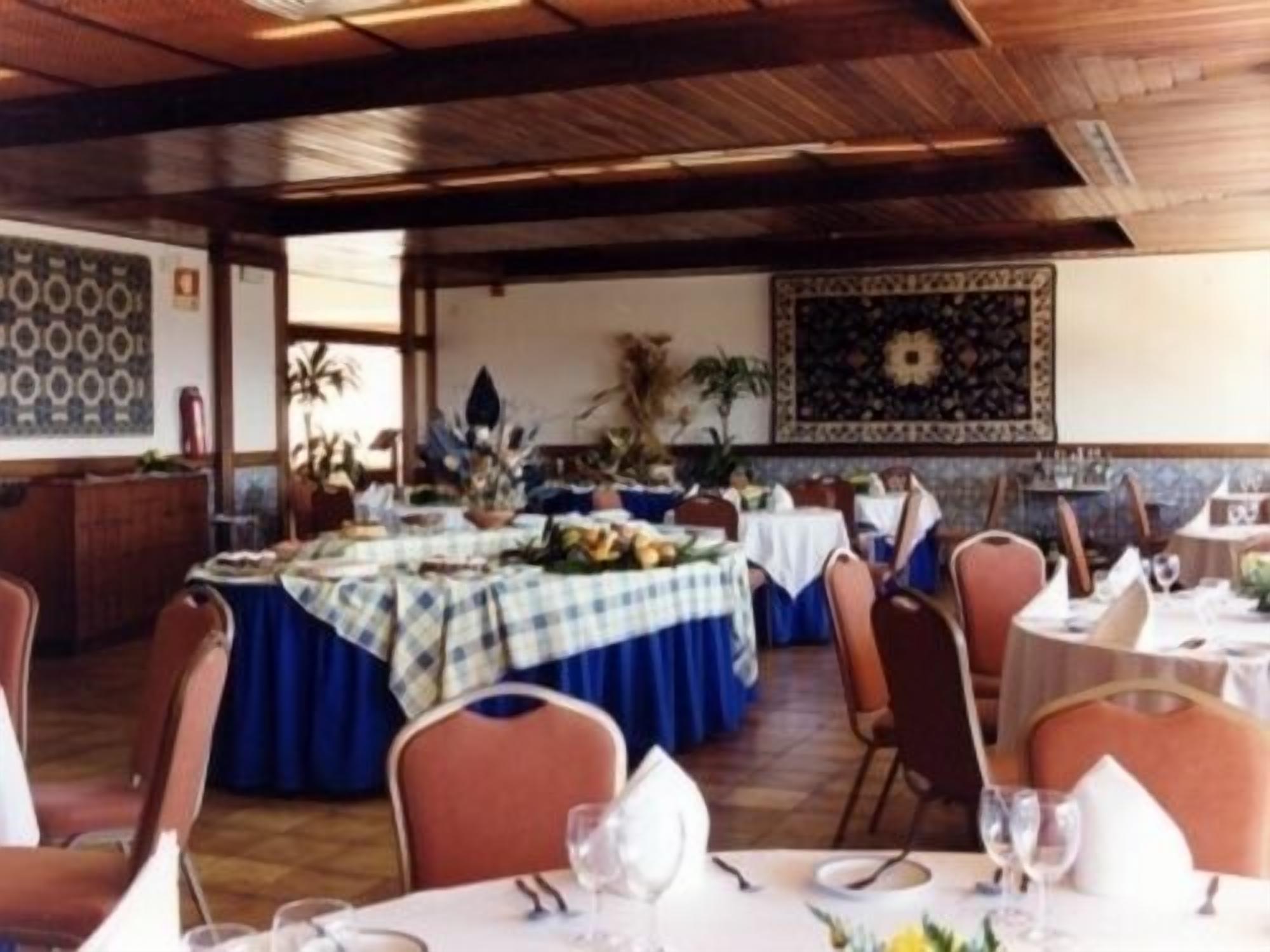 Um restaurante com várias mesas, cada uma disposta com toalhas brancas e guardanapos azuis.