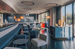 Um restaurante moderno com área de estar curva, mesas redondas e um balcão de bar.
