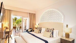 Quarto de hotel com cama grande, escrivaninha, cadeira e vista para o exterior.