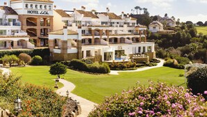 Um hotel com vários edifícios, piscina e um jardim bem cuidado.