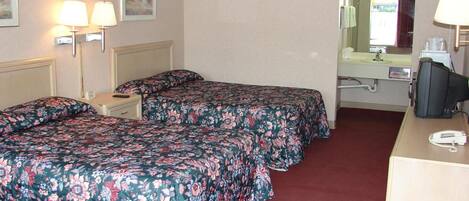 Quarto de hotel com duas camas, uma escrivaninha, um espelho e uma televisão.