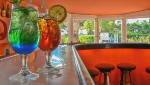 Duas bebidas geladas com canudos e rodelas de limão em um balcão de bar.
