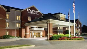 Hotel com fachada de tijolos, entrada coberta e bandeiras americanas.